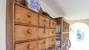 Uma cômoda de madeira com várias gavetas e uma prateleira com pratos azuis e brancos.