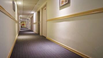Corredor de hotel com pisos cobertos de carpete e portas em ambos os lados.
