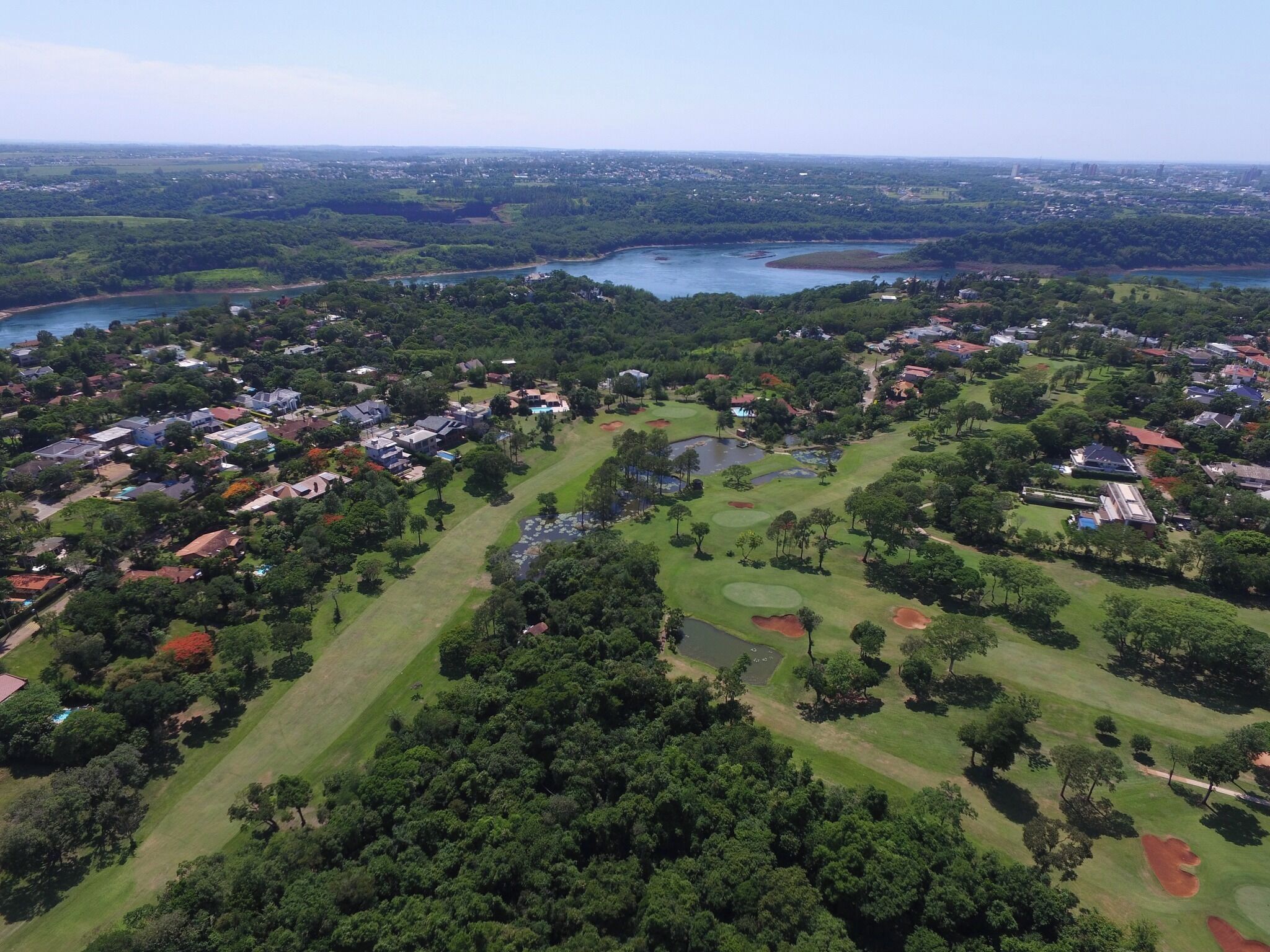 Vista aérea de um campo de golfe com um lago ao fundo.