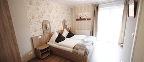 Quarto com cama de madeira, mesa de cabeceira, espelho e janela com cortinas.