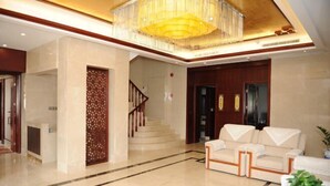 Um hall amplo com piso de mármore, escada e área de estar com sofá.