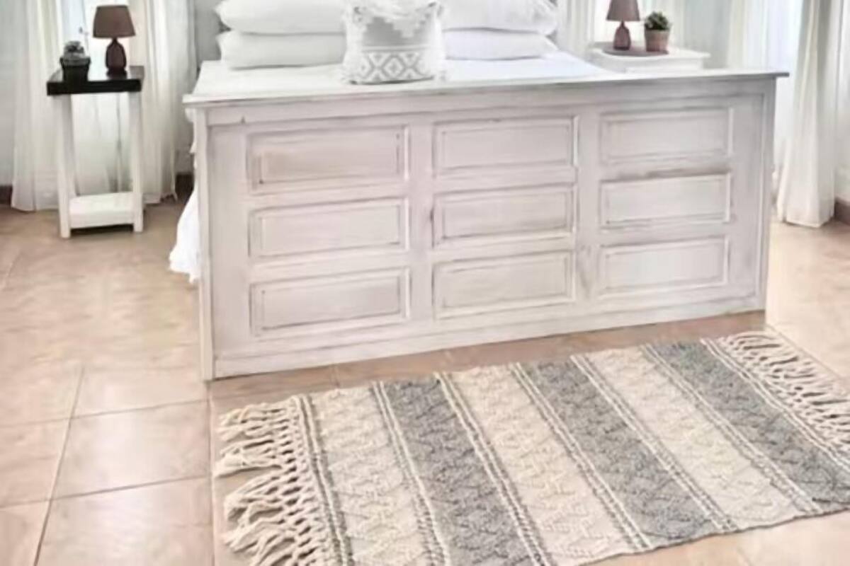 Quarto com uma cama grande, mesa de cabeceira com abajur e um enfeite na parede.