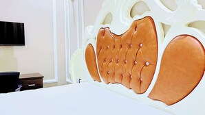 Cama com cabeceira branca e uma seção laranja com textura.
