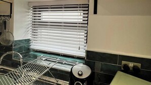 Uma cozinha com um letreiro 'Welcome to Bedlinog', uma chaleira, um varal e um micro-ondas.