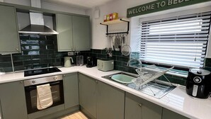 Uma cozinha moderna com armários cinza, forno embutido, pia e máquina de café.