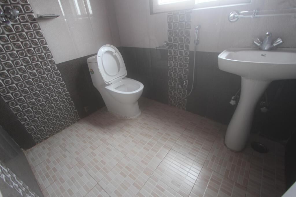 Casa de banho com sanita, lavatório e zona de duche.