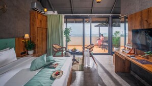 Quarto de hotel com cama, escrivaninha, televisão e varanda com vista.