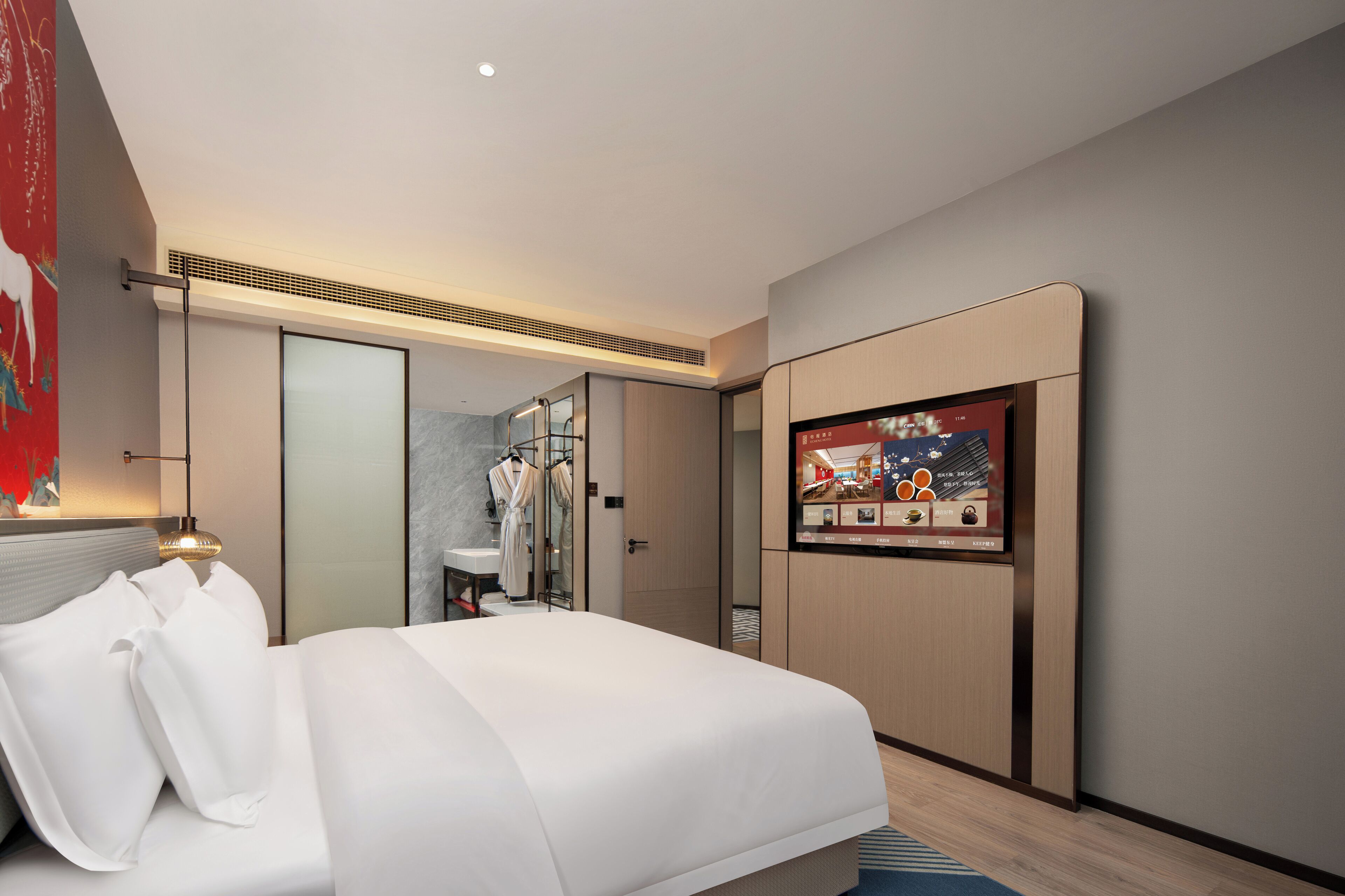 Quarto de hotel moderno com uma cama grande, televisão de tela plana na parede, banheiro com box de vidro e um quadro abstrato vermelho na parede.
