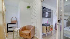 Uma sala de estar moderna com uma poltrona de couro, uma mesinha e uma porta de vidro que dá para uma cozinha.