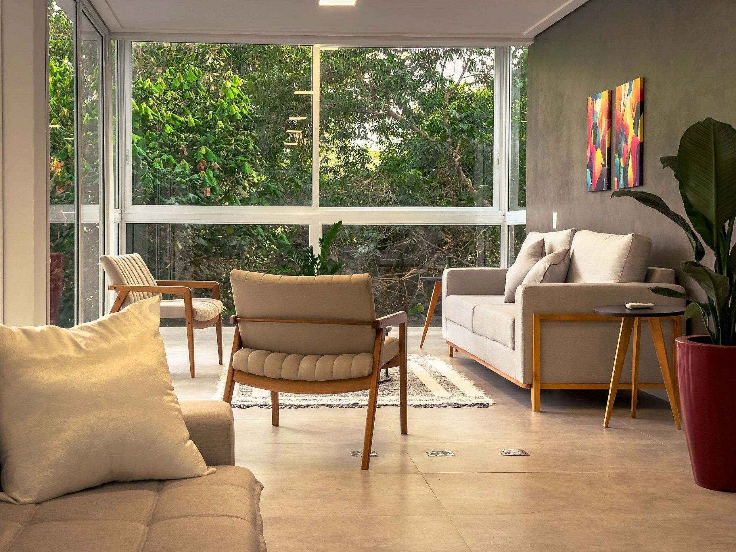 Uma sala de estar moderna com uma janela grande, um sofá, uma poltrona e uma mesa de centro.