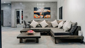 Uma sala de estar moderna com um sofá seccional, uma mesa de centro e um grande quadro abstrato na parede.