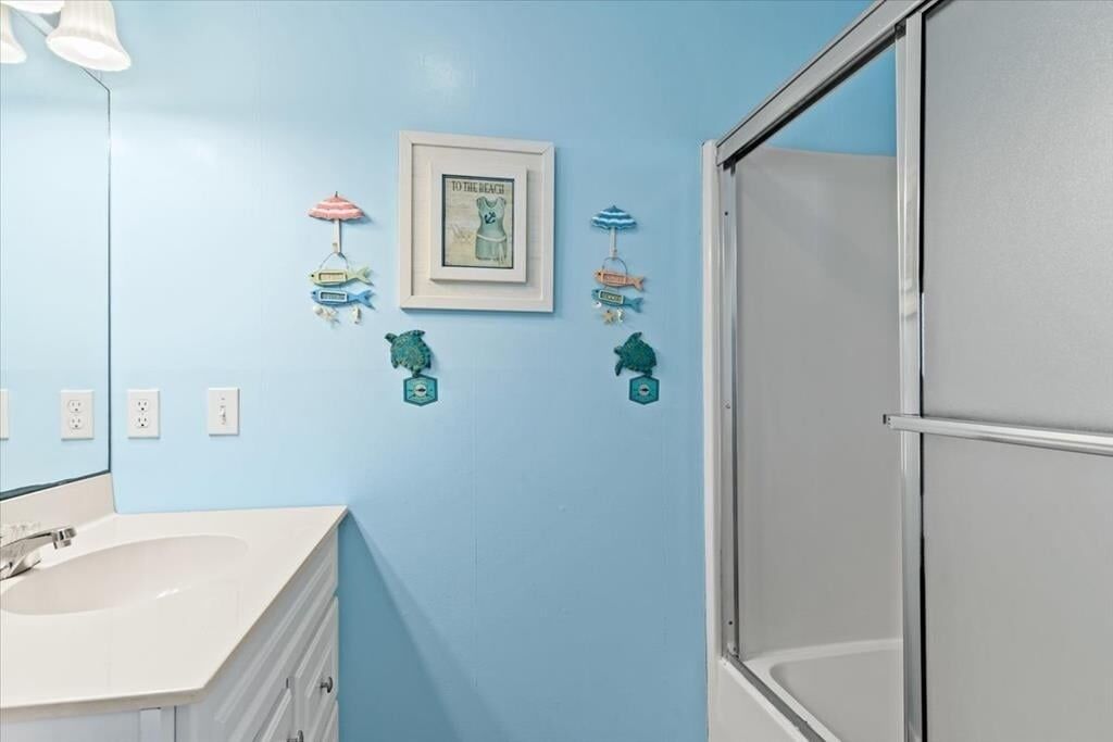 Uma casa de banho com uma pia branca, um quadro na parede e decorações de parede.