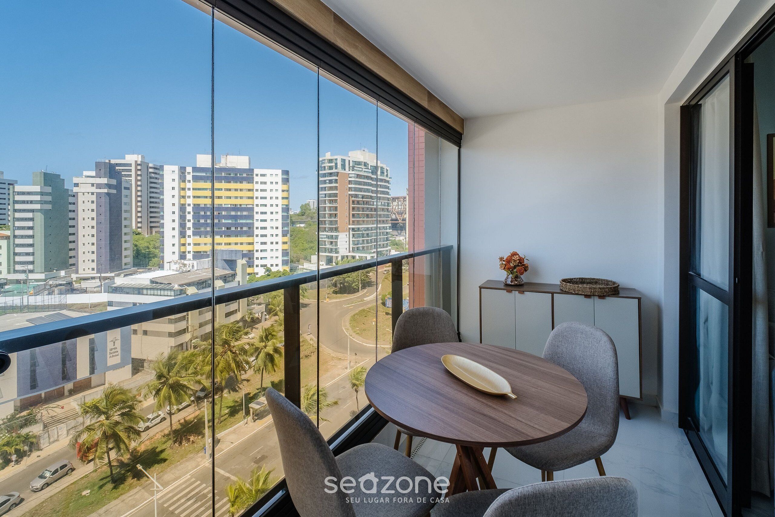 Uma varanda com mesa e cadeiras, vista para um horizonte urbano e design de interiores moderno.