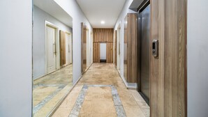 Corredor com porta central, ladeada por portas de madeira de ambos os lados, dando acesso a um espaço com acabamento em madeira.
