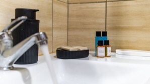 Uma pia de banheiro com torneira, sabonete e frascos de shampoo.