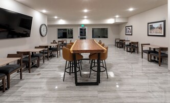 Uma sala de conferência com uma mesa comprida, cadeiras e um relógio na parede.