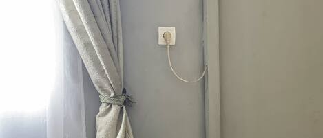 Uma cadeira com estrutura de madeira e assento acolchoado em um quarto com parede azul claro e uma tomada.