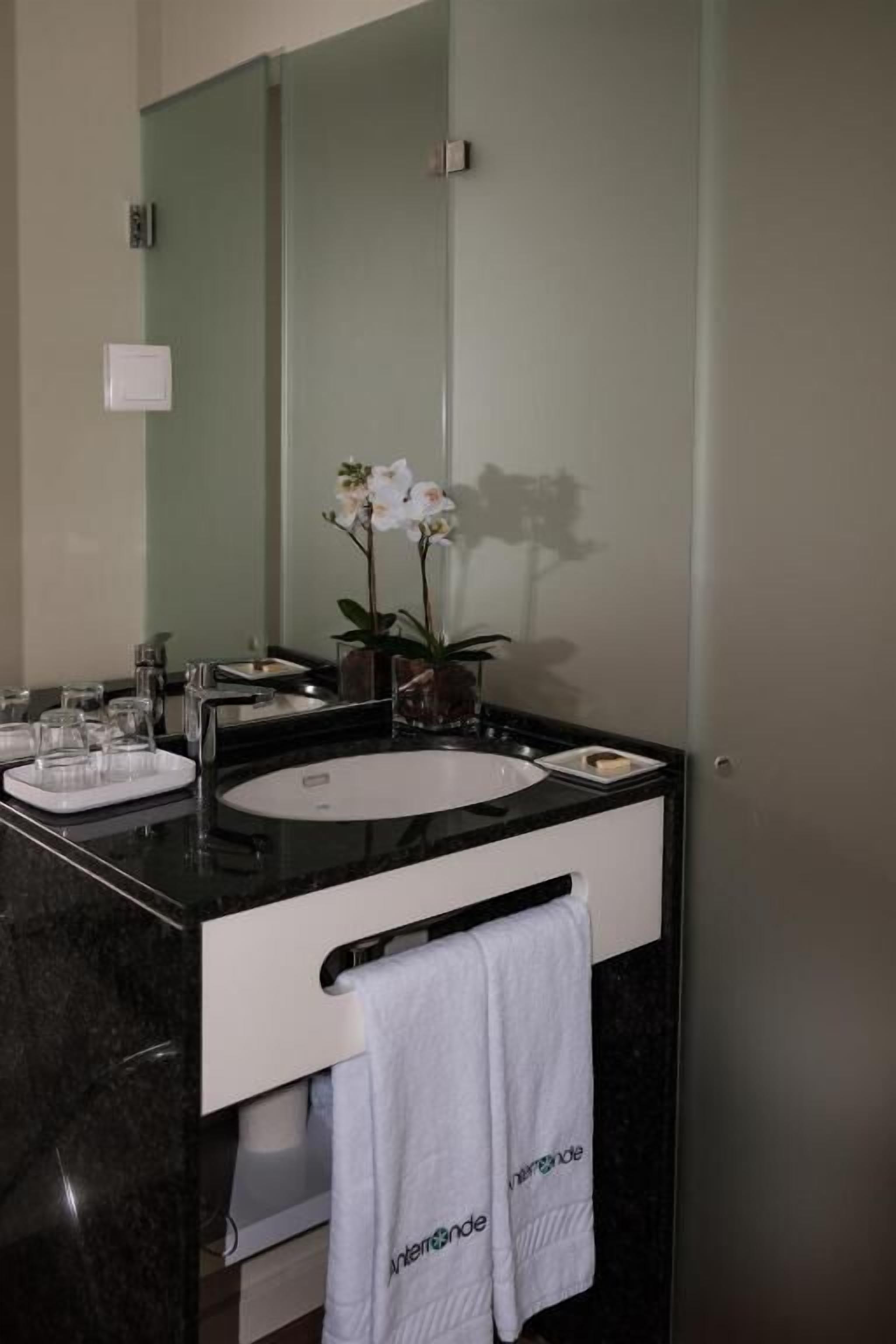 Um banheiro moderno com pia de granito preto, um espelho grande e uma toalha branca pendurada em um porta-toalhas.