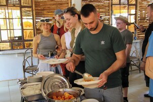 Uma mesa de buffet com vários recipientes de servir e uma panela grande de comida.