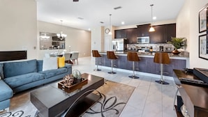 Uma sala de estar moderna com sofá, mesa de centro e área de cozinha com balcão e assentos.
