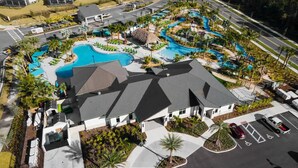 Vista aérea de um resort com piscina, estacionamento e um edifício com telhado escuro.