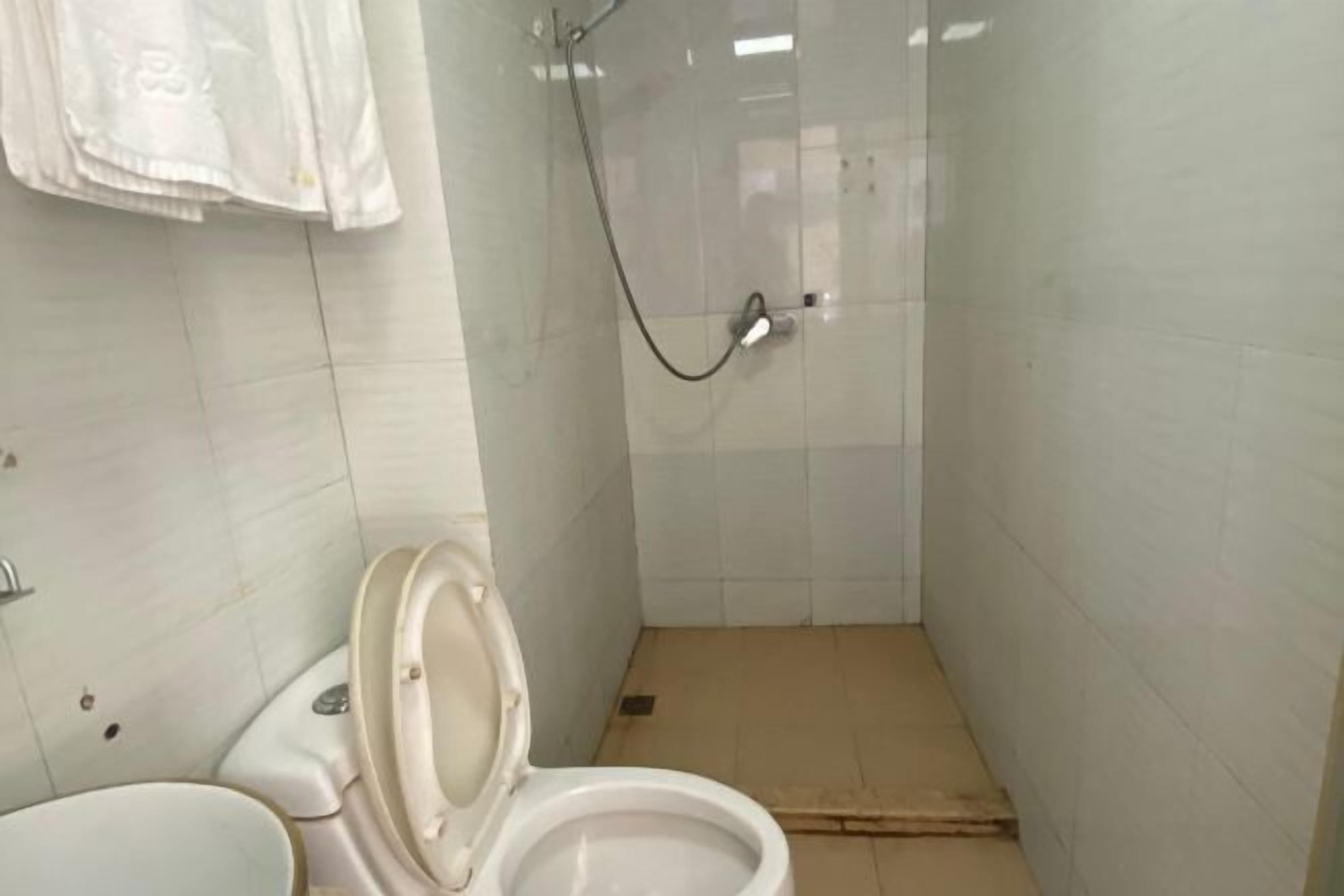 Casa de banho com sanita, chuveiro e lavatório.