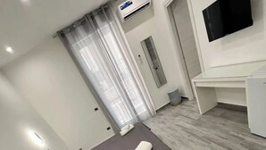 Quarto de hotel moderno com cama, escrivaninha e televisão de tela plana.