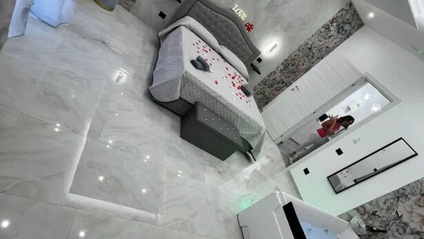 Quarto de hotel moderno com piso de mármore, uma cama grande, uma banheira embutida e área de chuveiro.