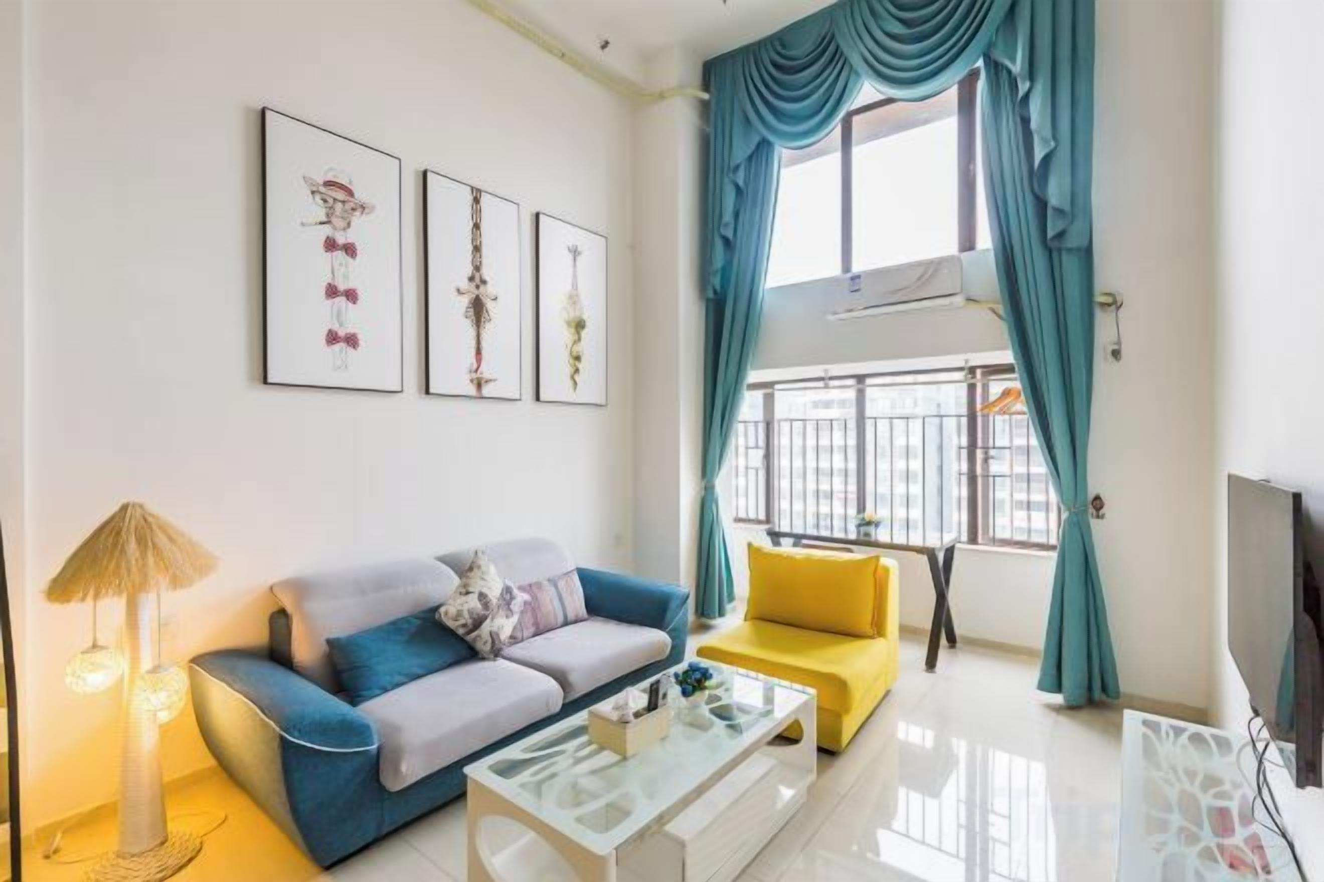 Uma sala de estar com sofá, mesa de centro, poltrona amarela e televisão.