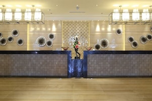 Uma área de recepção com piso de azulejos, balcão de atendimento e elementos decorativos fixados na parede.