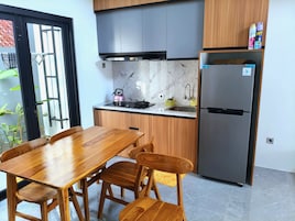 Cozinha compacta com armários de madeira, geladeira de aço inoxidável, fogão a gás e pia.