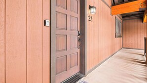 Uma porta de madeira com o número "22" acima, uma luminária pequena e um vigário de madeira no teto.