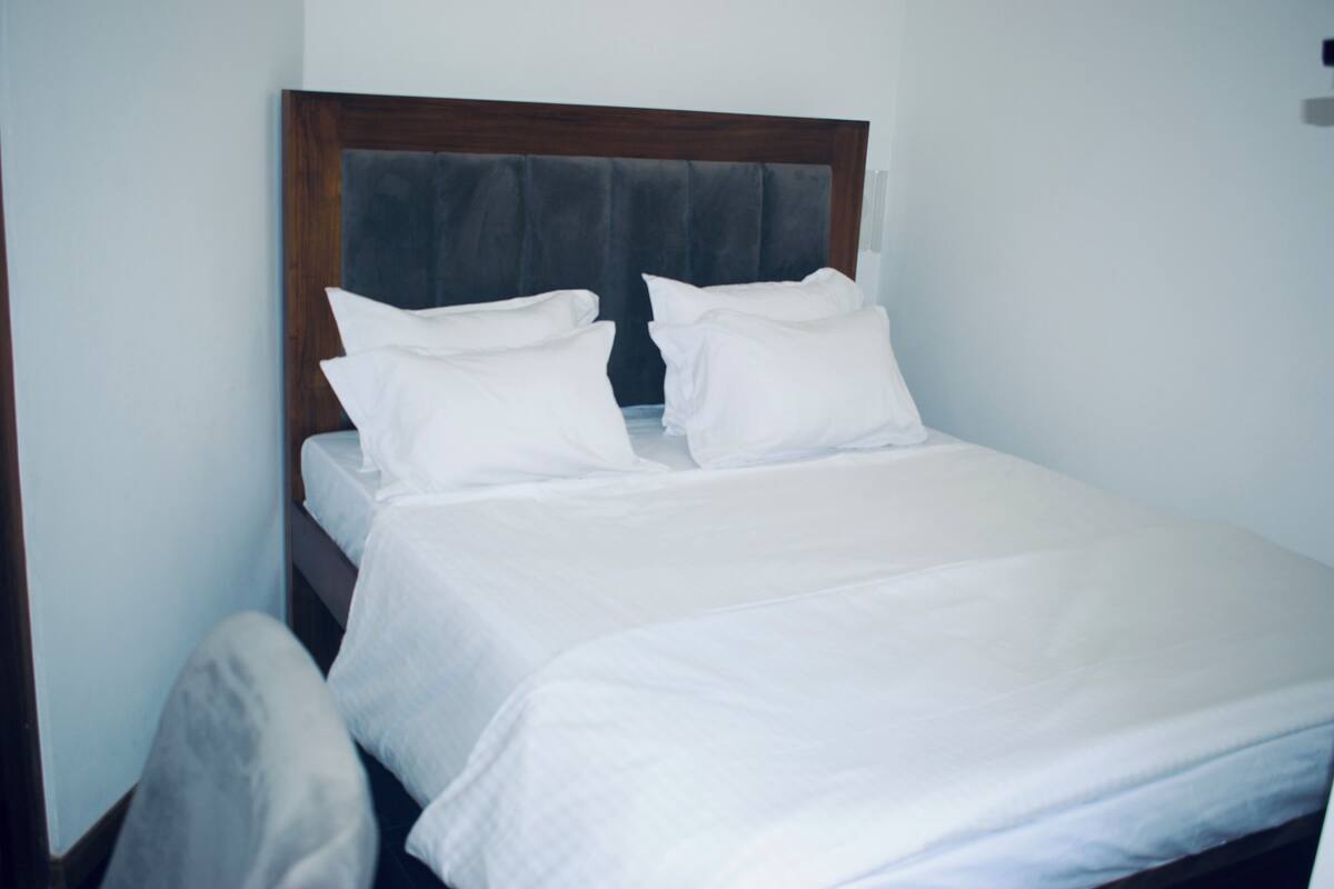 Uma cama bem arrumada com cabeceira de madeira e roupa de cama branca.