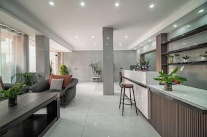 Cozinha moderna com ilha central, banquetas de bar e área de estar com sofá e mesa de centro.