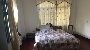 Quarto com cama, cortinas e tapete vermelho.