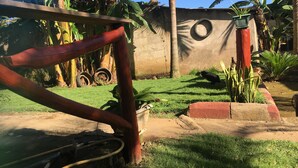 Um jardim com parede de concreto, estrutura de madeira e diversas plantas.