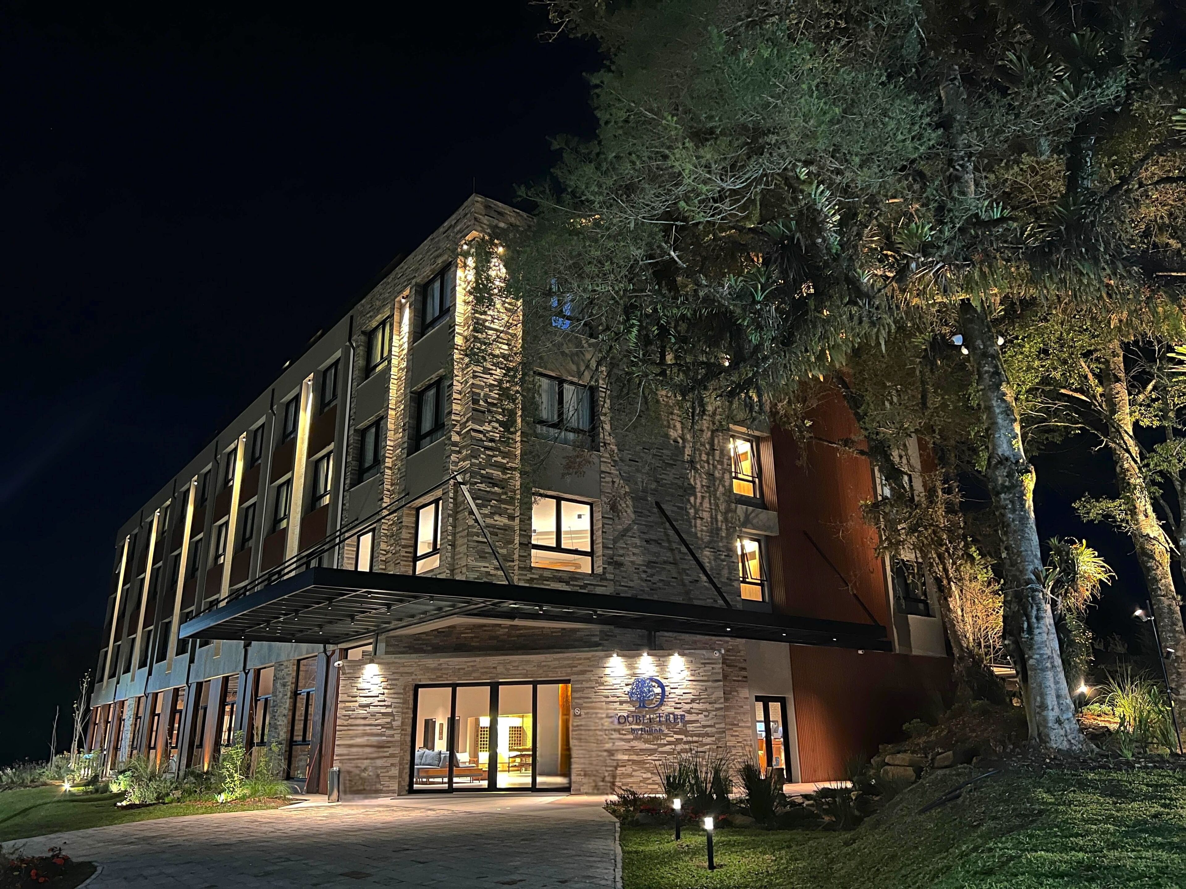 Um hotel com vários andares, fachada de pedra, janelas amplas e entrada bem iluminada.