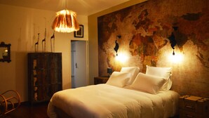 Quarto com cama grande, mural de mapa-múndi, luminária pendente e armário de madeira.