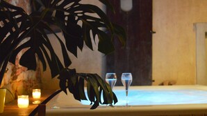 Um quarto com uma banheira, dois copos e velas sobre uma mesa de madeira.