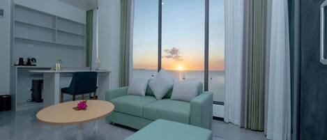 Uma sala de estar moderna com um sofá, uma mesa redonda e vista para o pôr do sol através de grandes janelas.