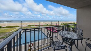 Uma varanda com piscina, área de estar ao ar livre e vista para a praia e o cais.