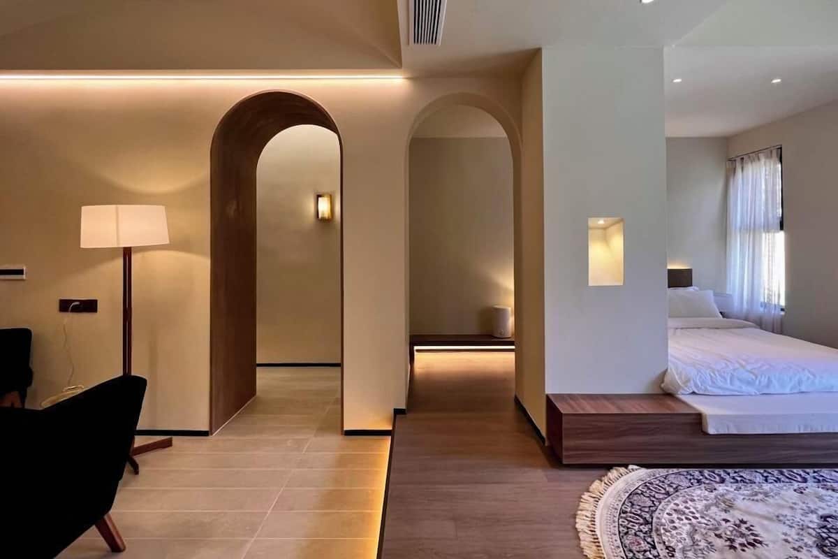 Quarto de hotel moderno com cama, escrivaninha, cadeira e abajur.