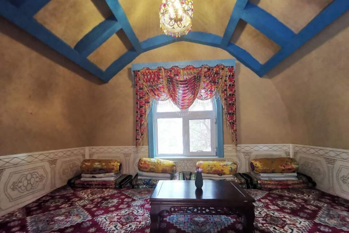 Um quarto com carpete estampado, uma mesa de madeira e uma janela com cortinas.
