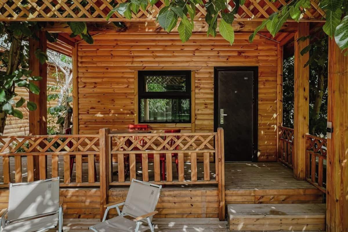 Uma cabana de madeira com varanda, duas cadeiras e uma porta.