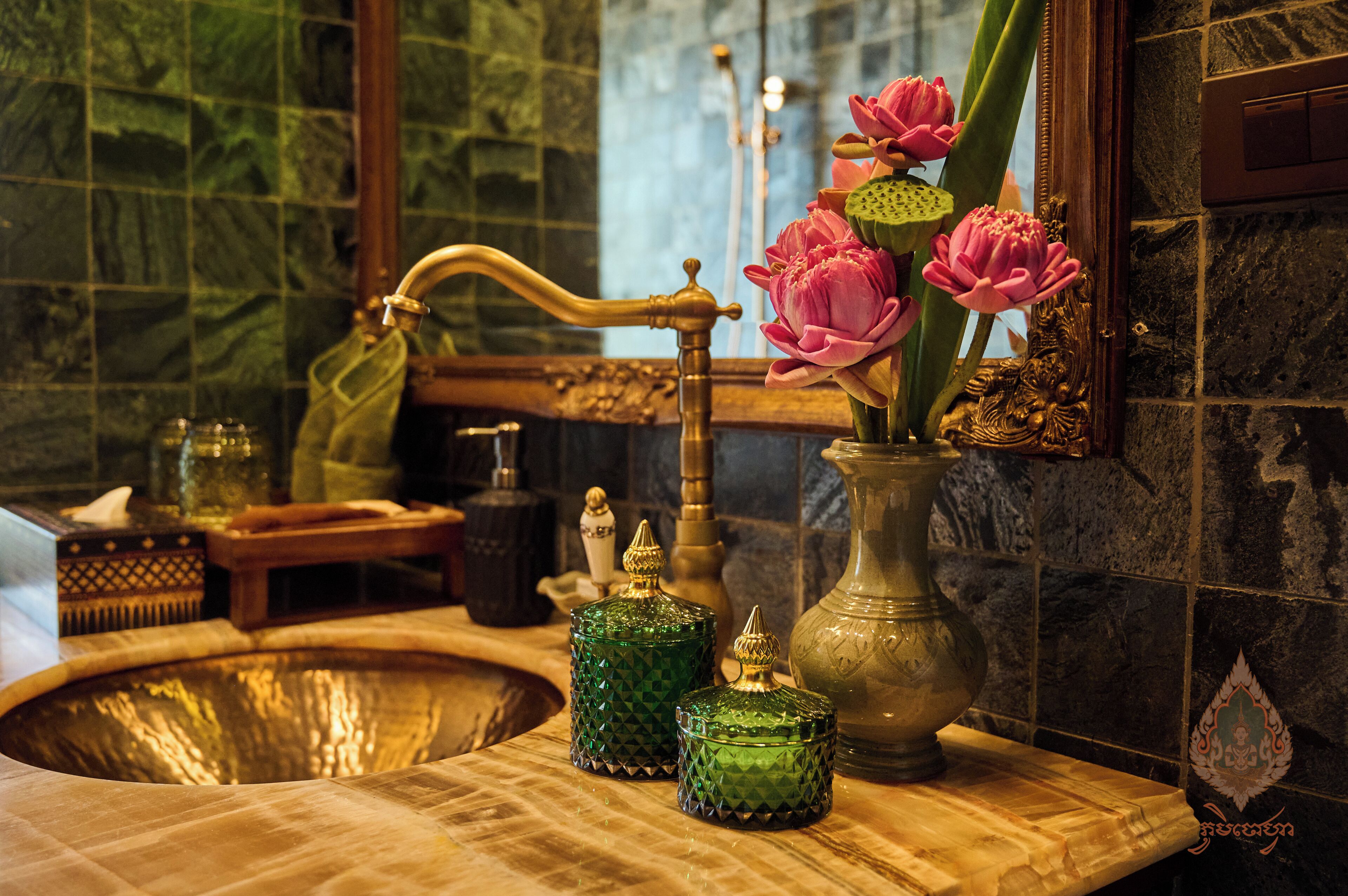 Um banheiro com banheira, espelho e objetos decorativos, incluindo um vaso com flores e um recipiente de vidro verde.
