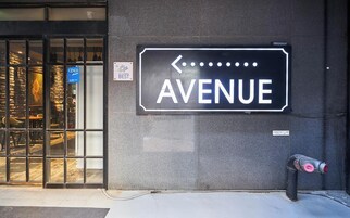 Placa de rua com a palavra 'AVENUE', uma seta apontando para a esquerda, uma placa com a palavra 'BEST' e um hidrante na calçada.