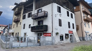 Um edifício de vários andares com varandas, uma placa indicando 'ESCLUSIVO' e um portão com uma bicicleta estacionada na frente.