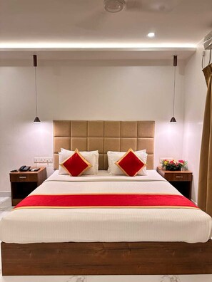 Quarto de hotel moderno com uma cama grande, duas mesas de cabeceira, um telefone e um criado-mudo.