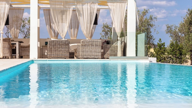 Piscina com toldos brancos e mobiliário de vime.