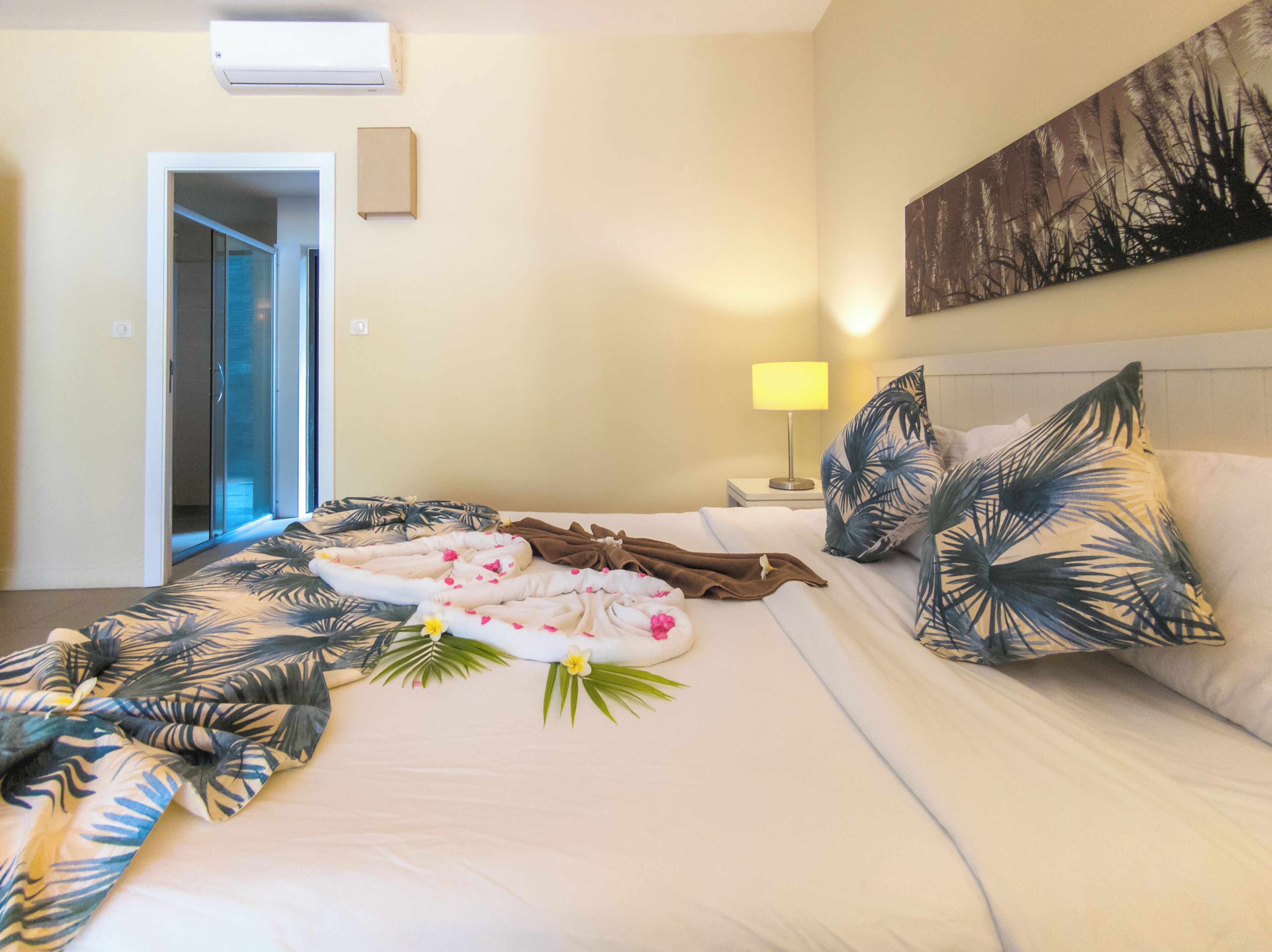 Quarto de hotel com cama, mesa de cabeceira, abajur e um quadro na parede.